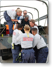ICS responders helping a disaster survivor off of the back of a truck.